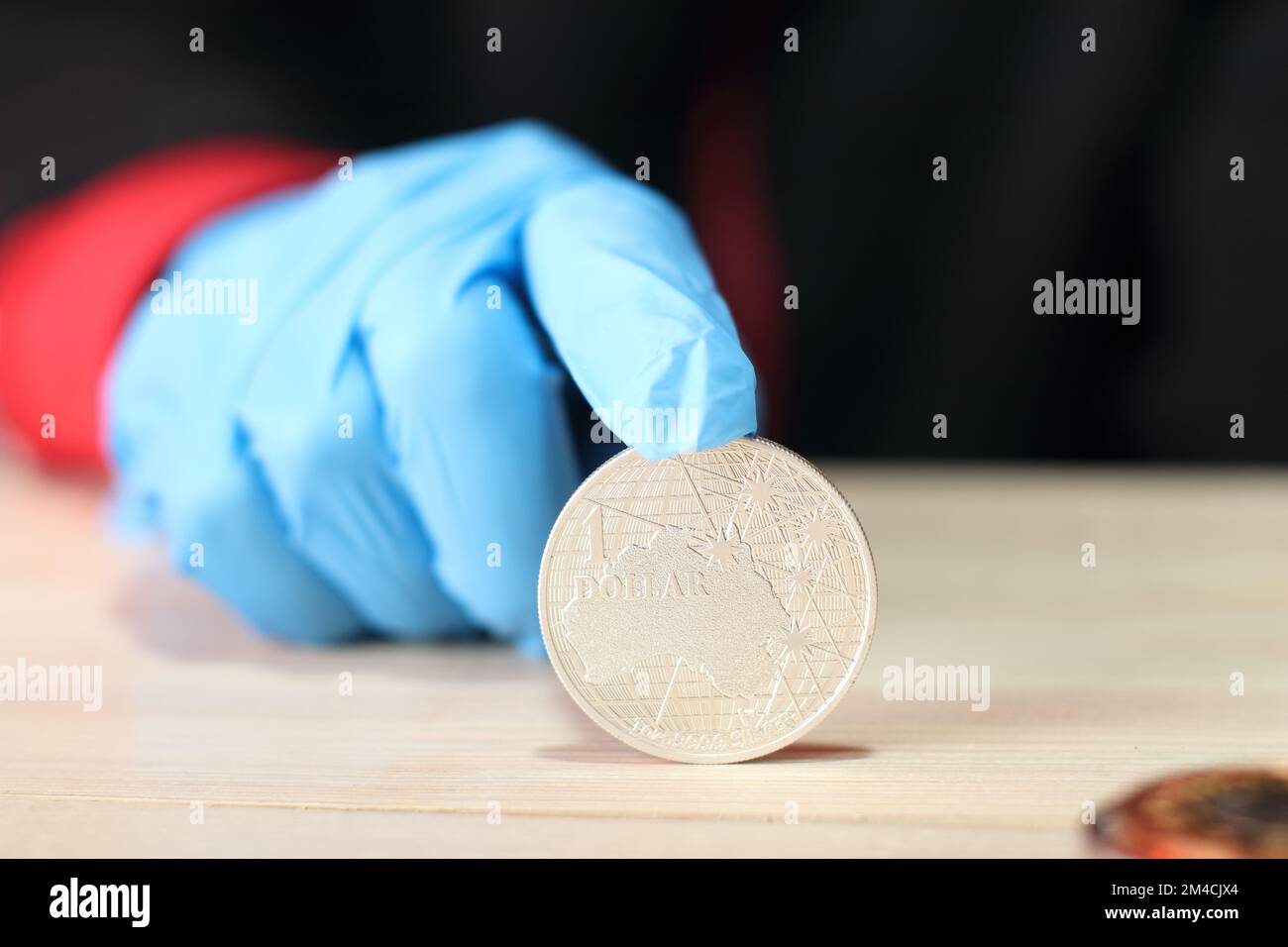 silver australian coin under the finger on the table vertically and ...