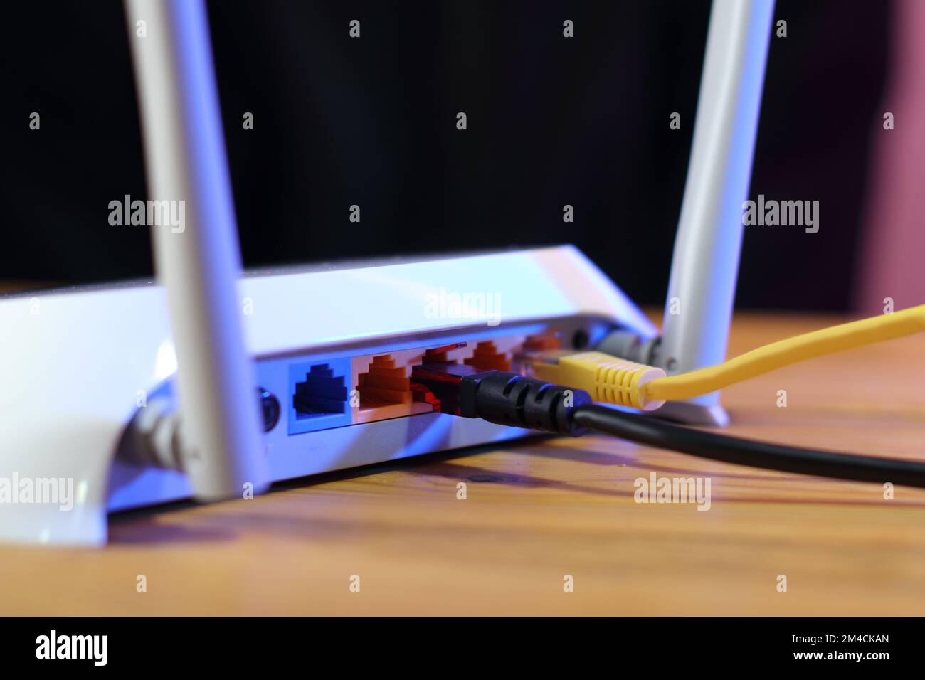 back of router with ethernet ports and connected cables on wooden table ...