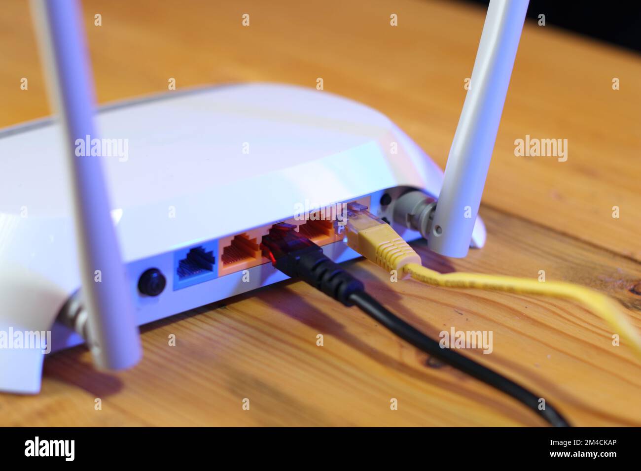 back of router with ethernet ports and connected cables on wooden table ...