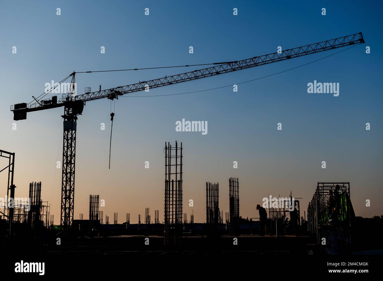 Industrial construction cranes and building silhouettes over sun at ...