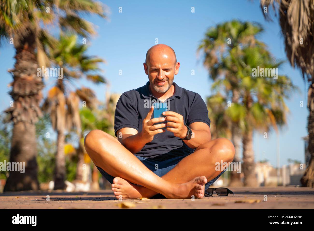 Bald man talking and using his smartphone in a tropical country Stock ...