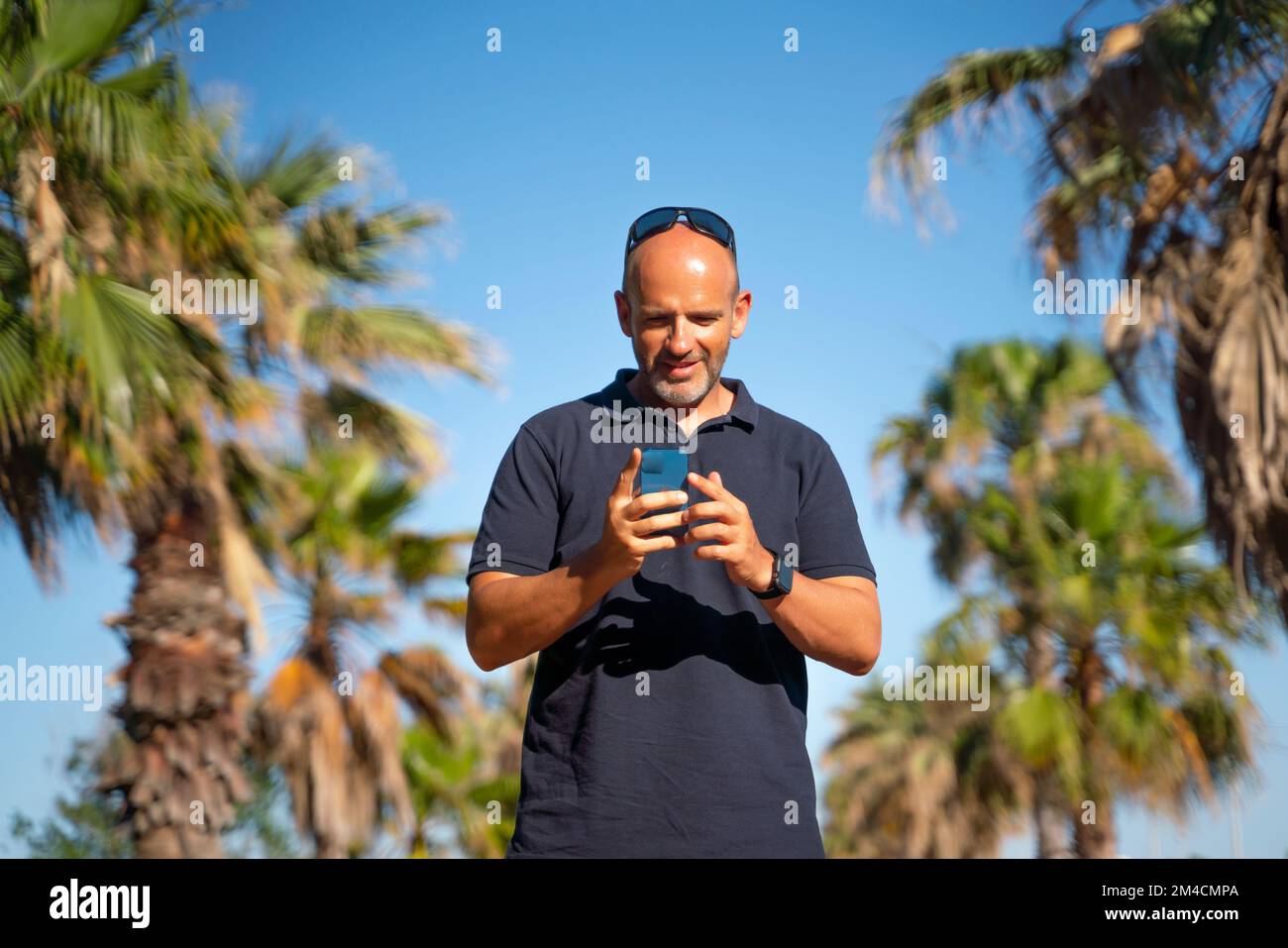 Bald man talking and using his smartphone in a tropical country Stock ...