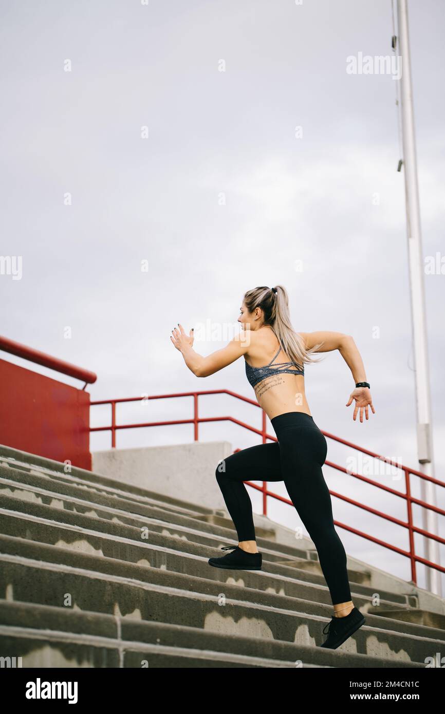 Muscular woman running stairs outside in black leggings and spor Stock ...
