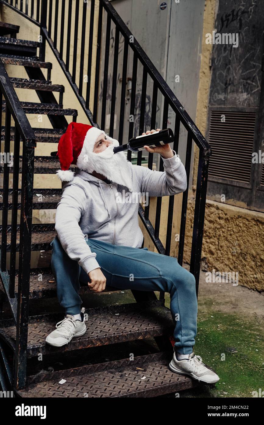 Homeless Santa drinking wine and rummaging through garbage bins Stock ...