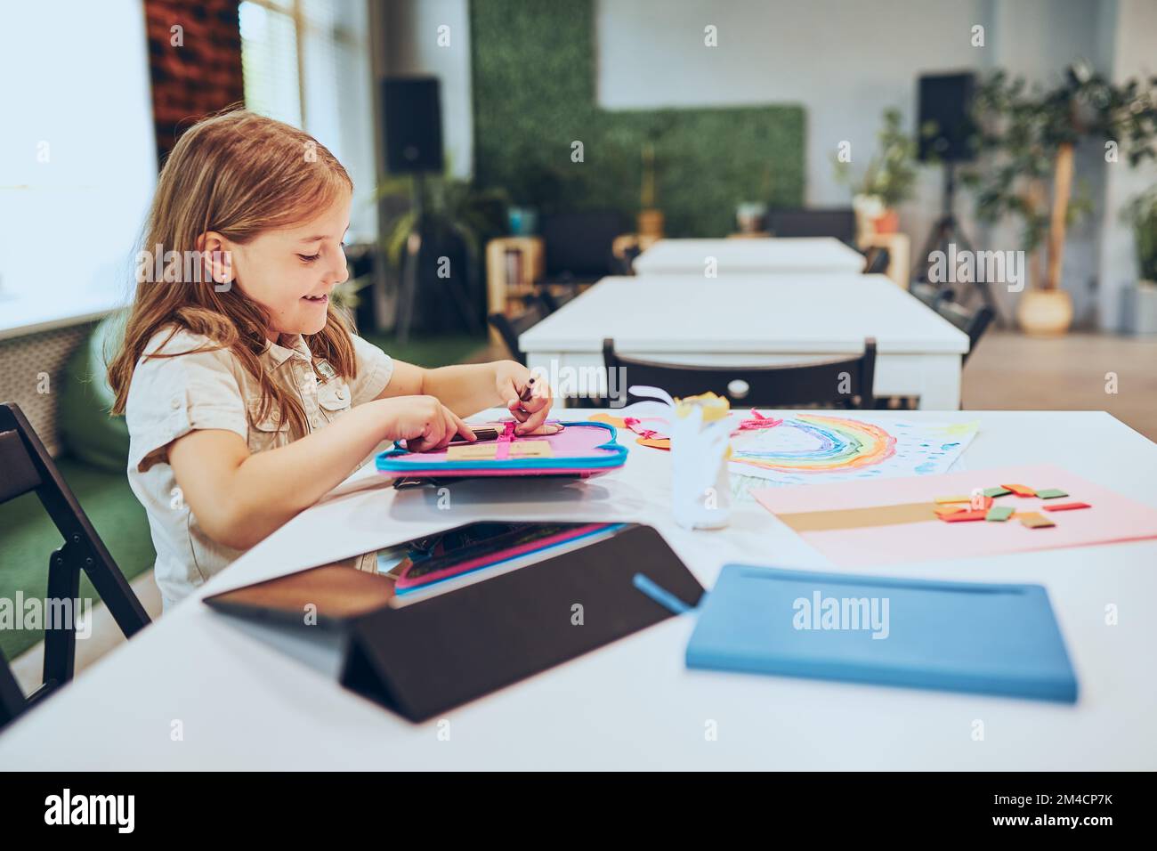 Schoolgirl doing homework sitting at desk in afterschool club. Girl ...