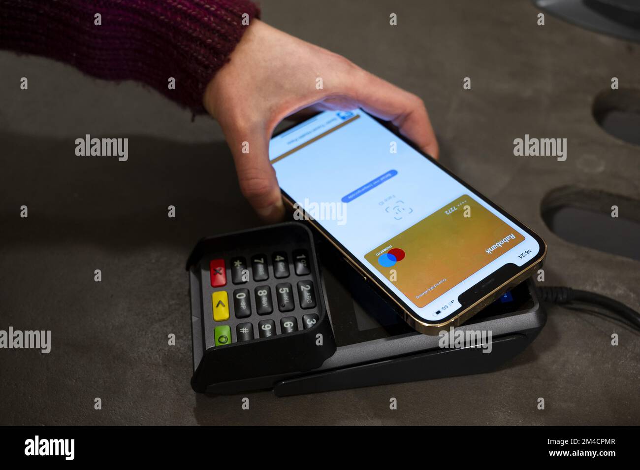 AMSTERDAM - ILLUSTRATIVE - A debit card payment with a smartphone in a ...