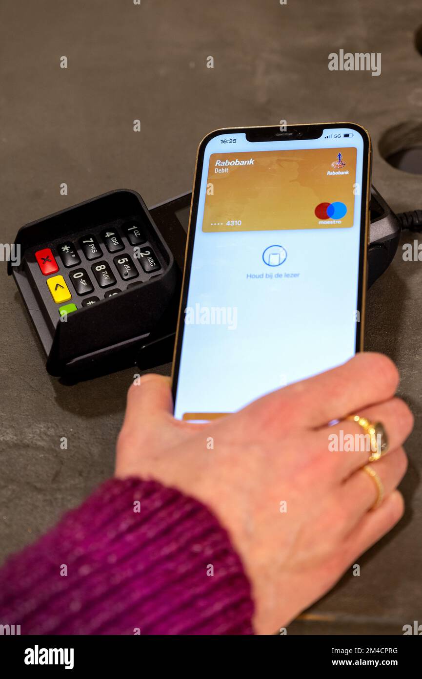 AMSTERDAM - ILLUSTRATIVE - A debit card payment with a smartphone in a ...