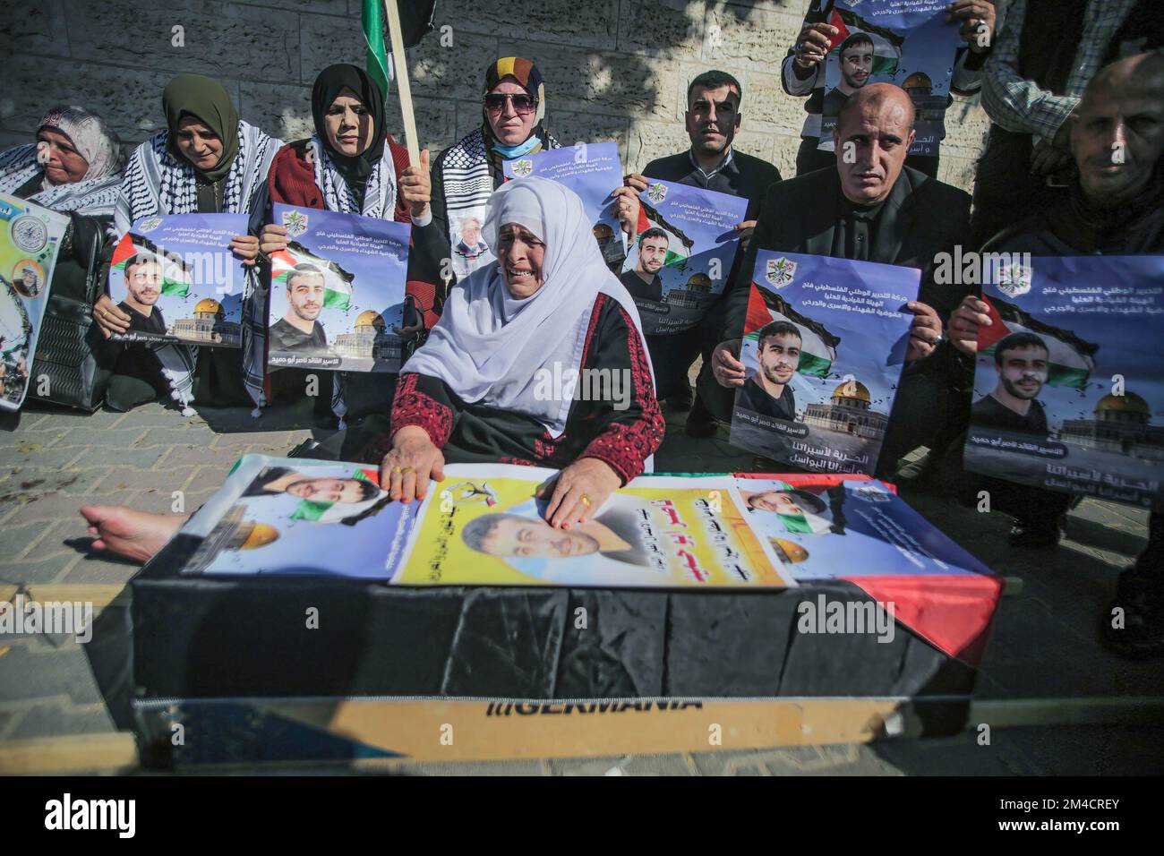Palestinians mourn while sitting around a mock coffin as they hold a ...
