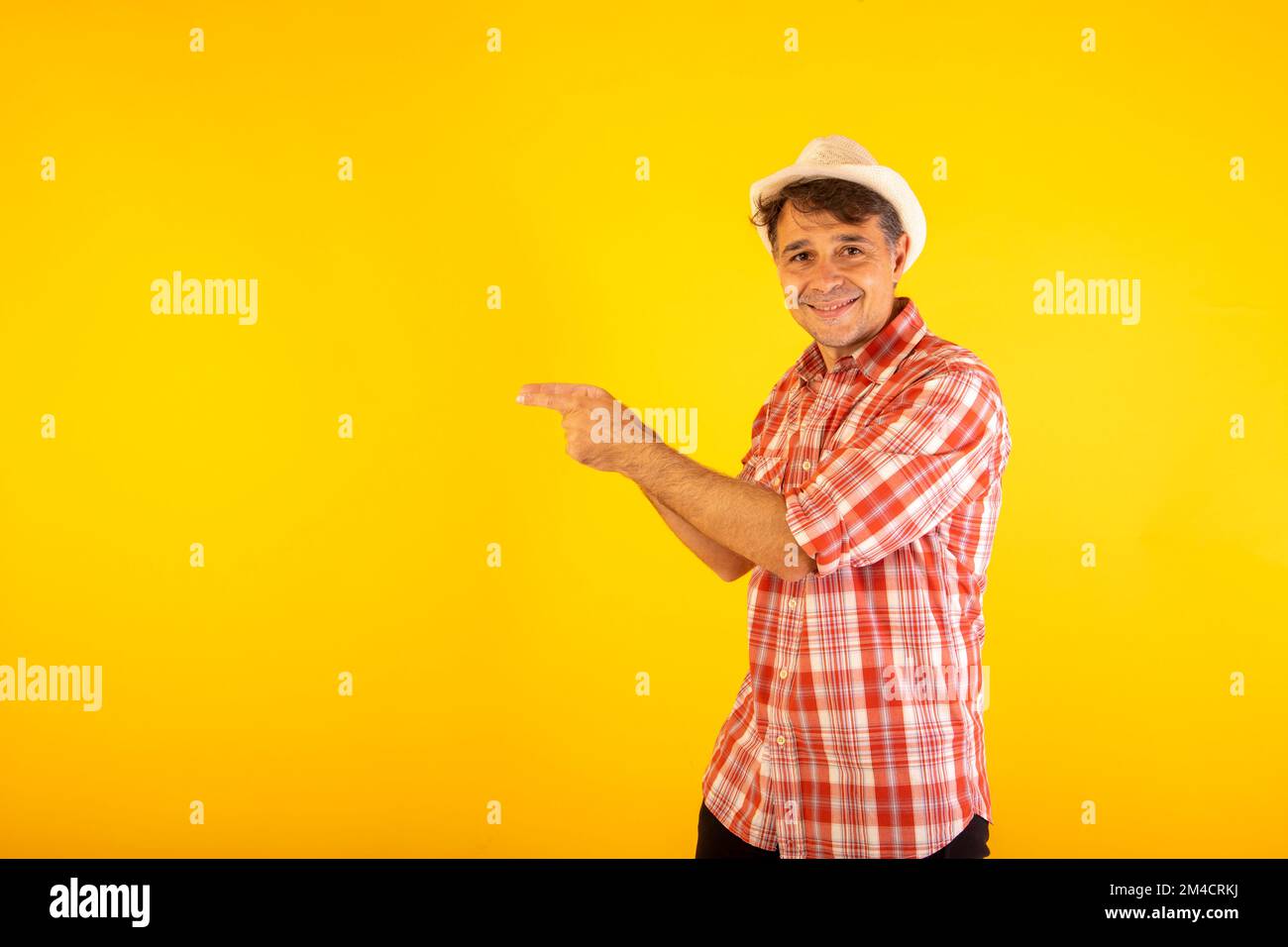 Man in hat and colorful checkered shirt pointing to the side with his ...