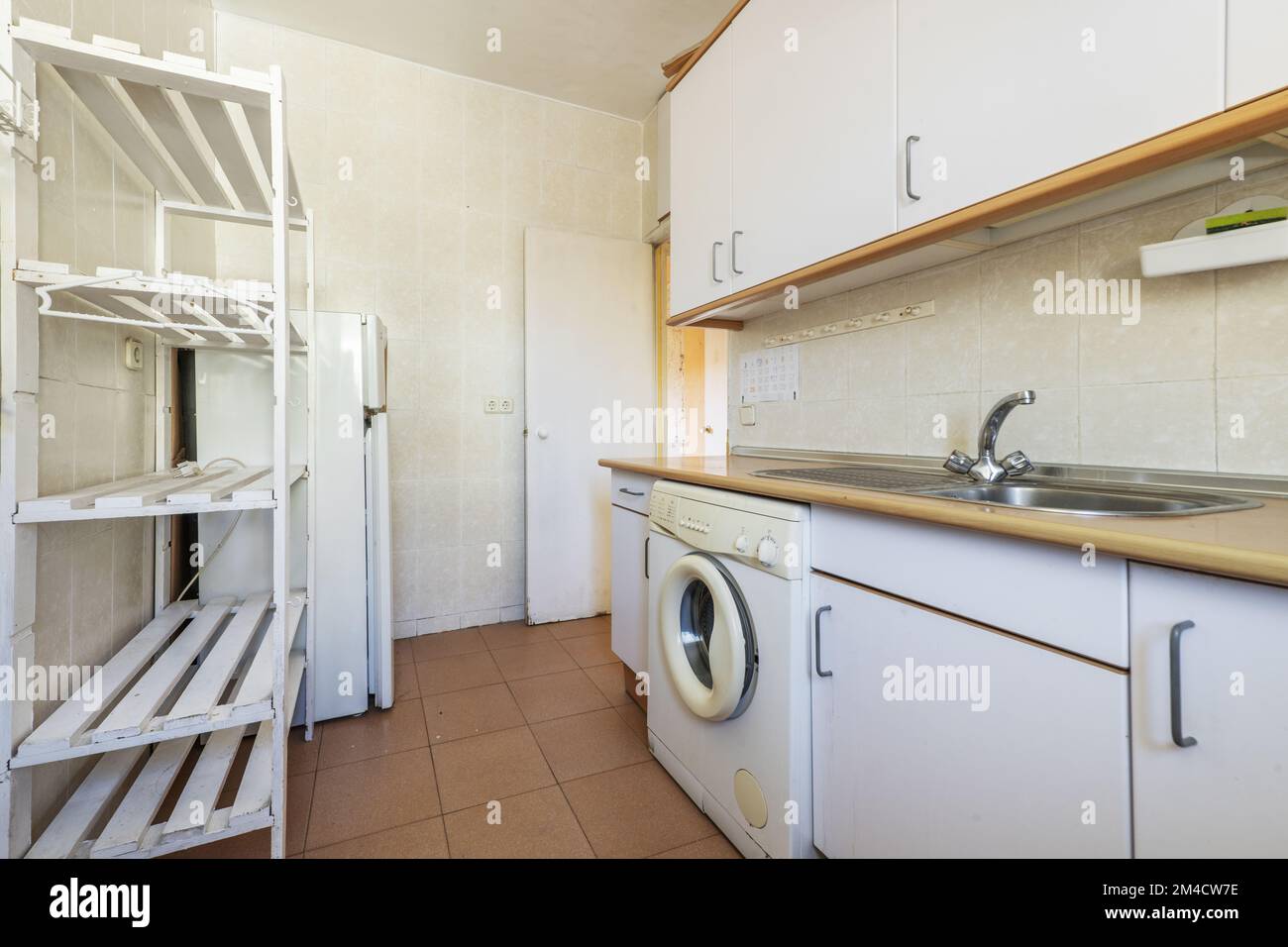 Old kitchen with worn cabinets and white painted wooden shelving Stock ...