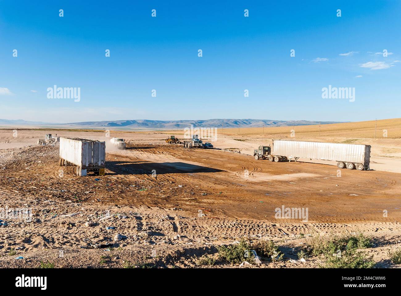 Three soil compactors and a watering truck on flat land in an active ...