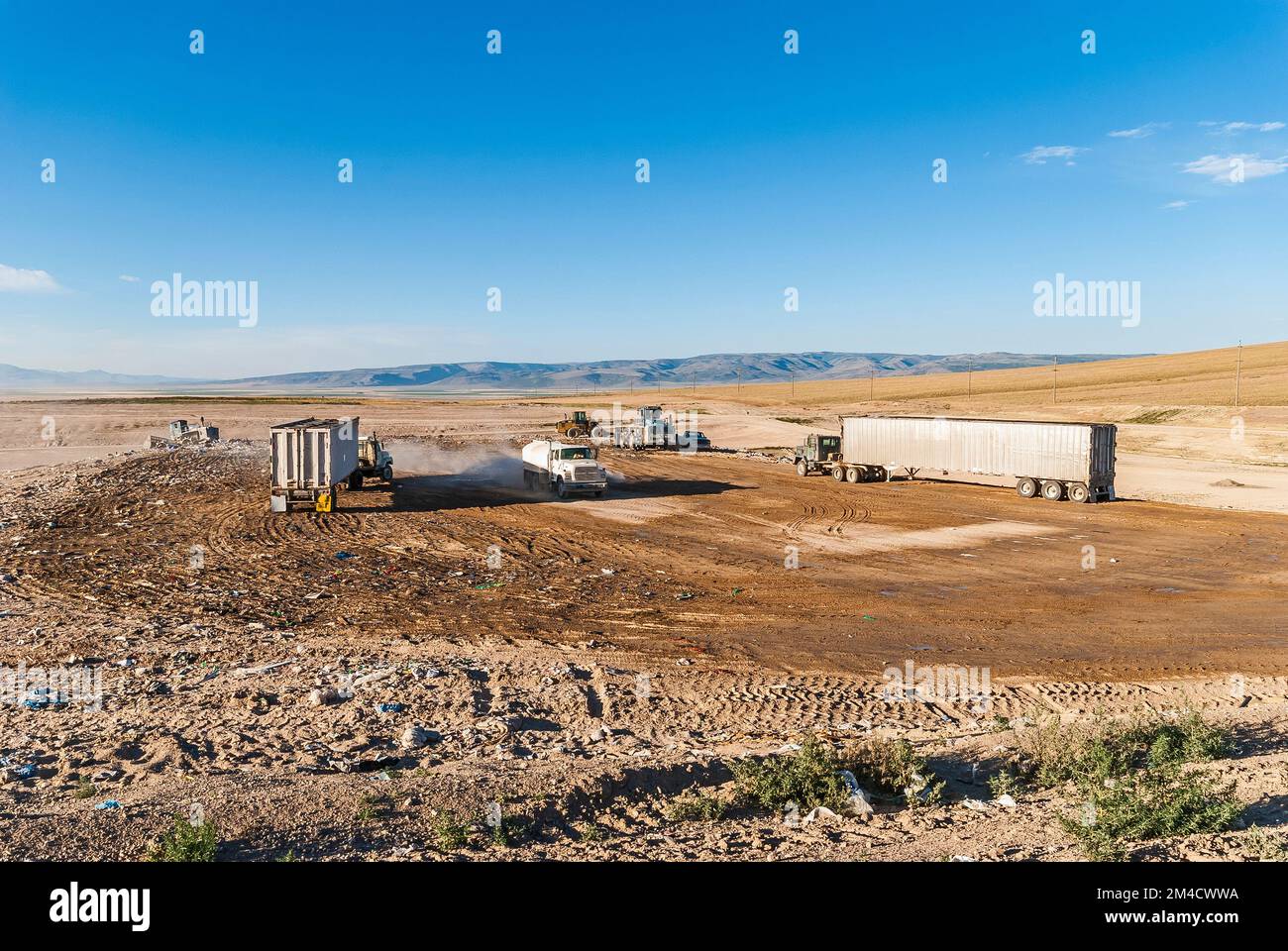 Three soil compactors and a watering truck on flat land in an active ...