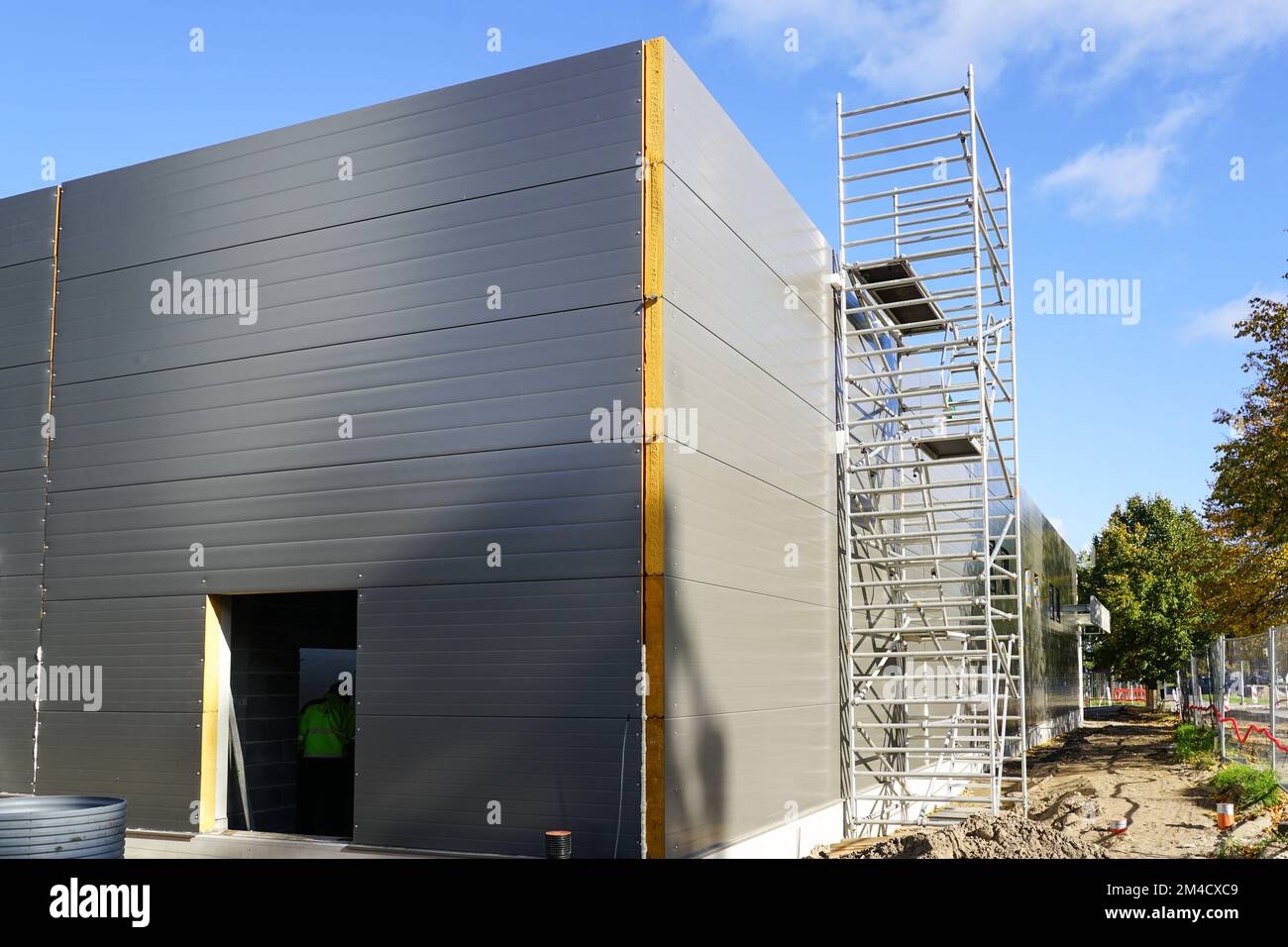 Gray sandwich panel facade of a unfinished warehouse building, tubular ...