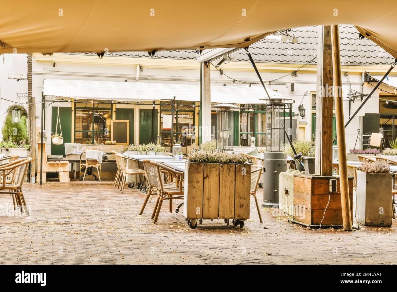an outdoor dining area with tables and umbrellas on the outside patio, surrounded by plants and ...