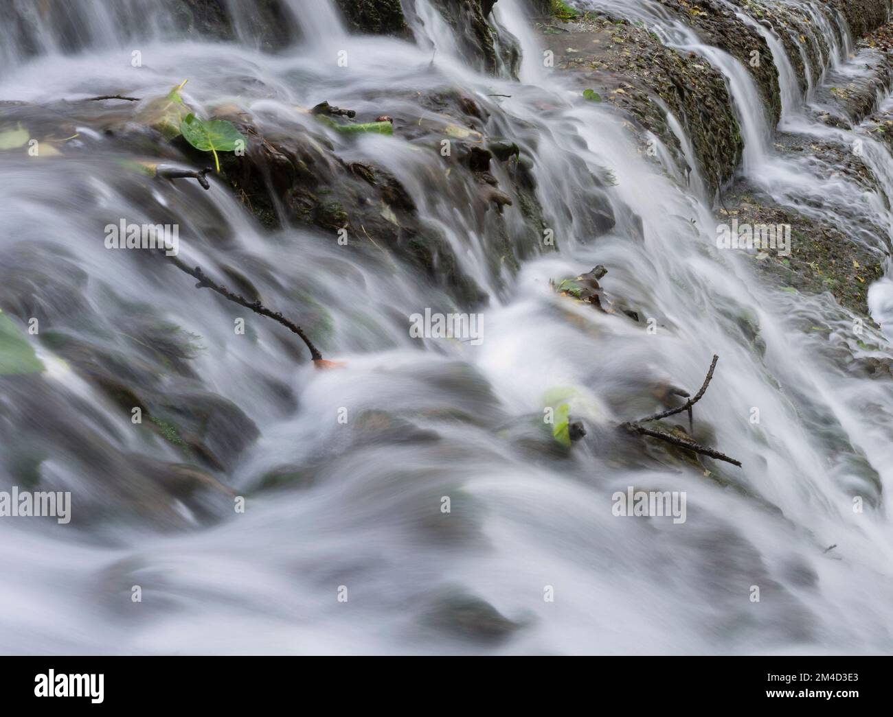 The long-exposure shot of the waterfall flowing down the stone cascade ...