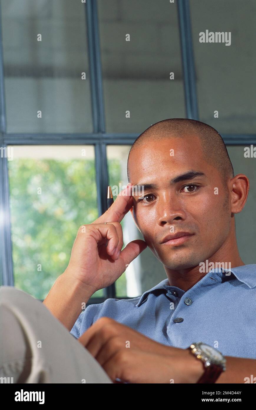 young man pausing while reading to look at the camera with his hand up ...