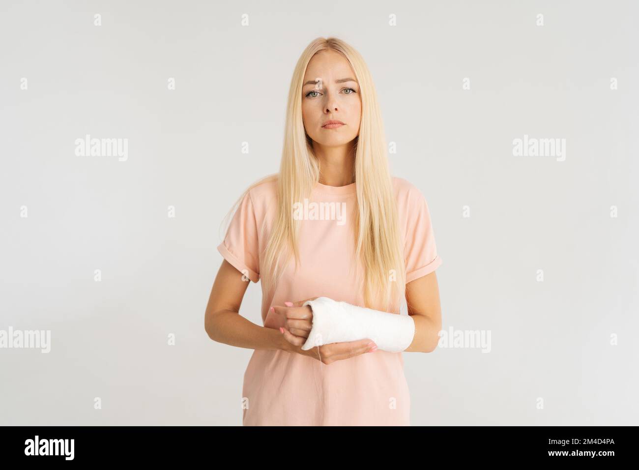 Studio portrait of sad injured blonde young woman with broken arm ...