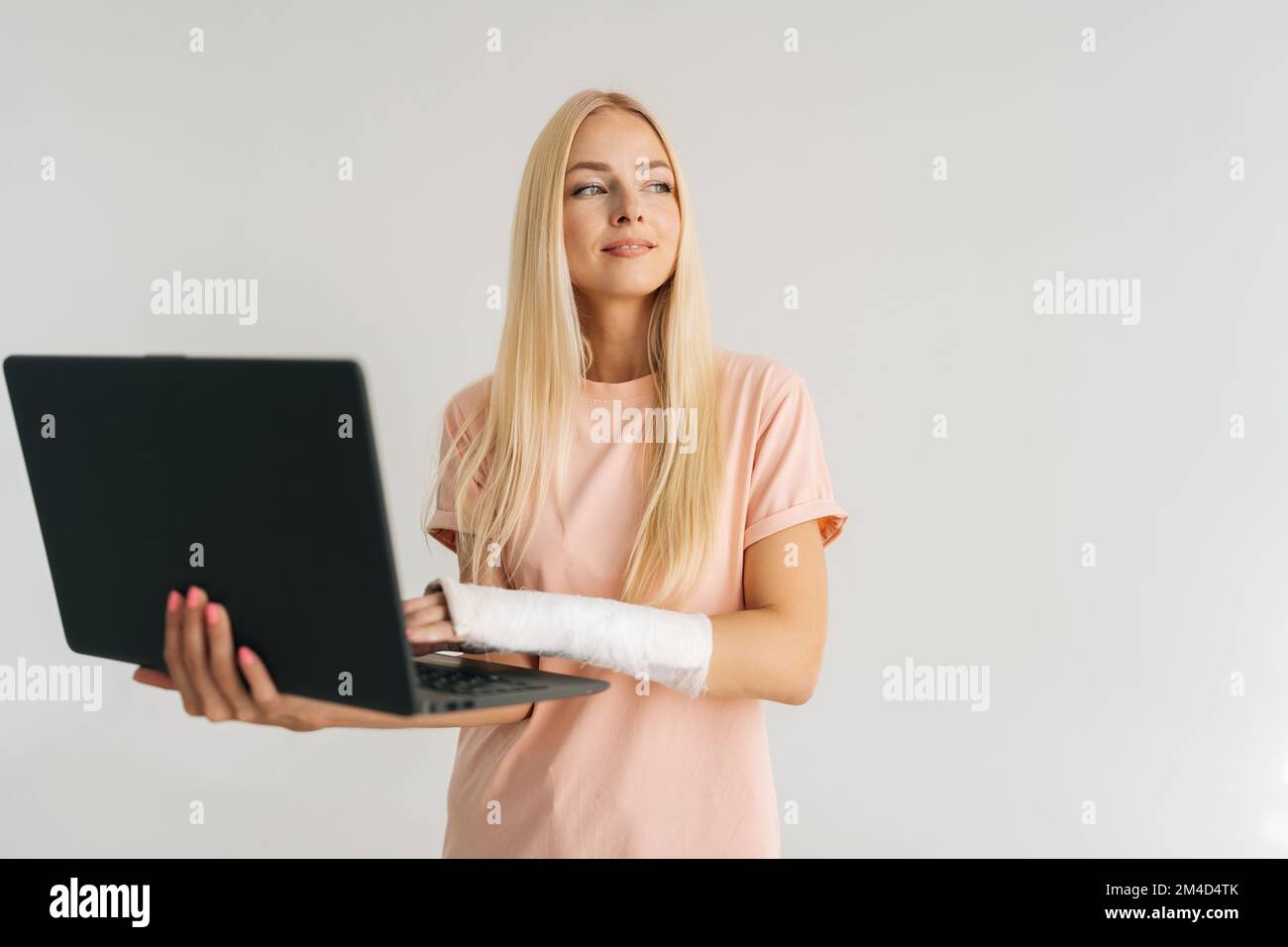 Portrait of smiling injured young woman with broken arm wrapped in ...