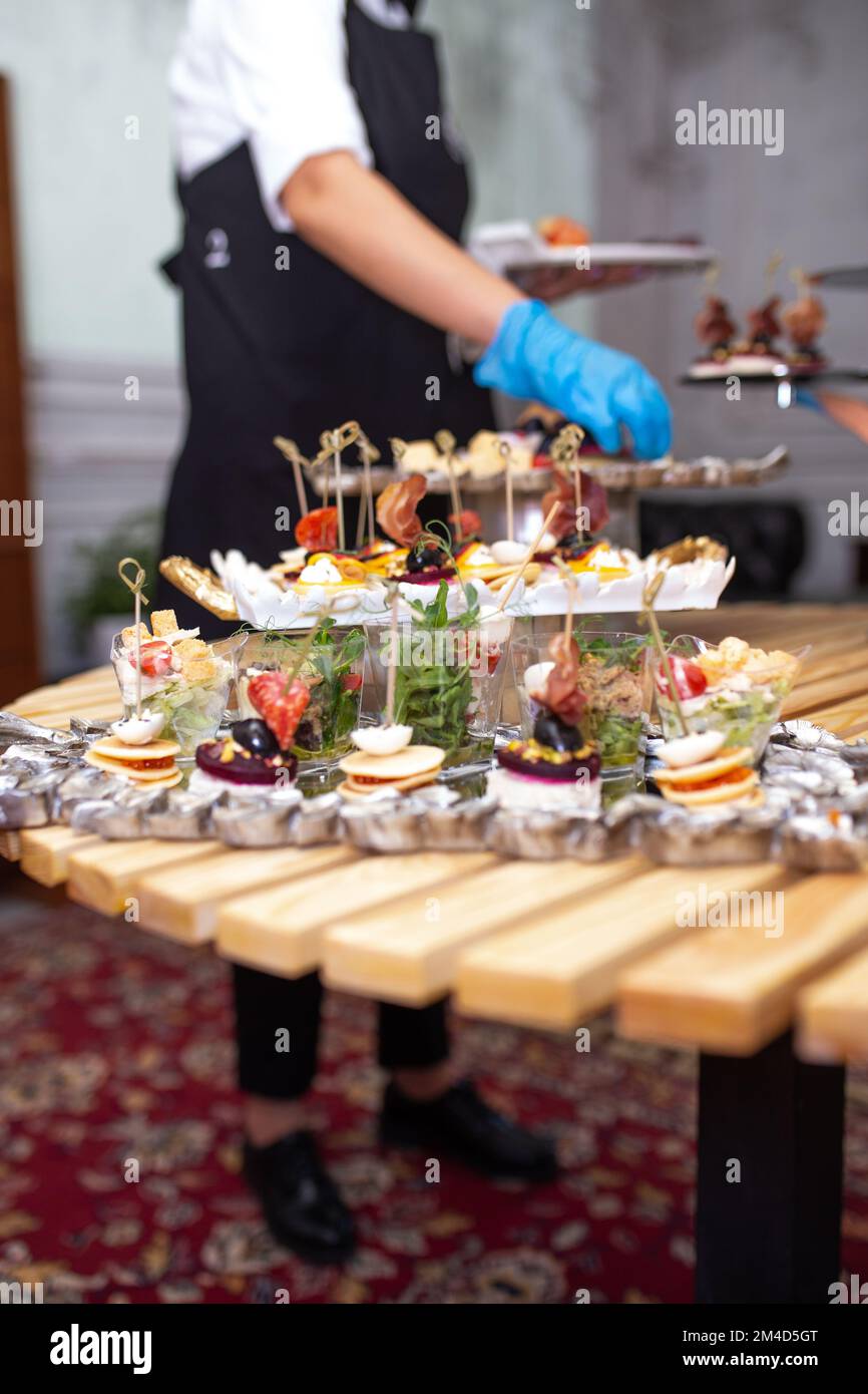 the waiter serves a table with snacks at the buffet Stock Photo - Alamy