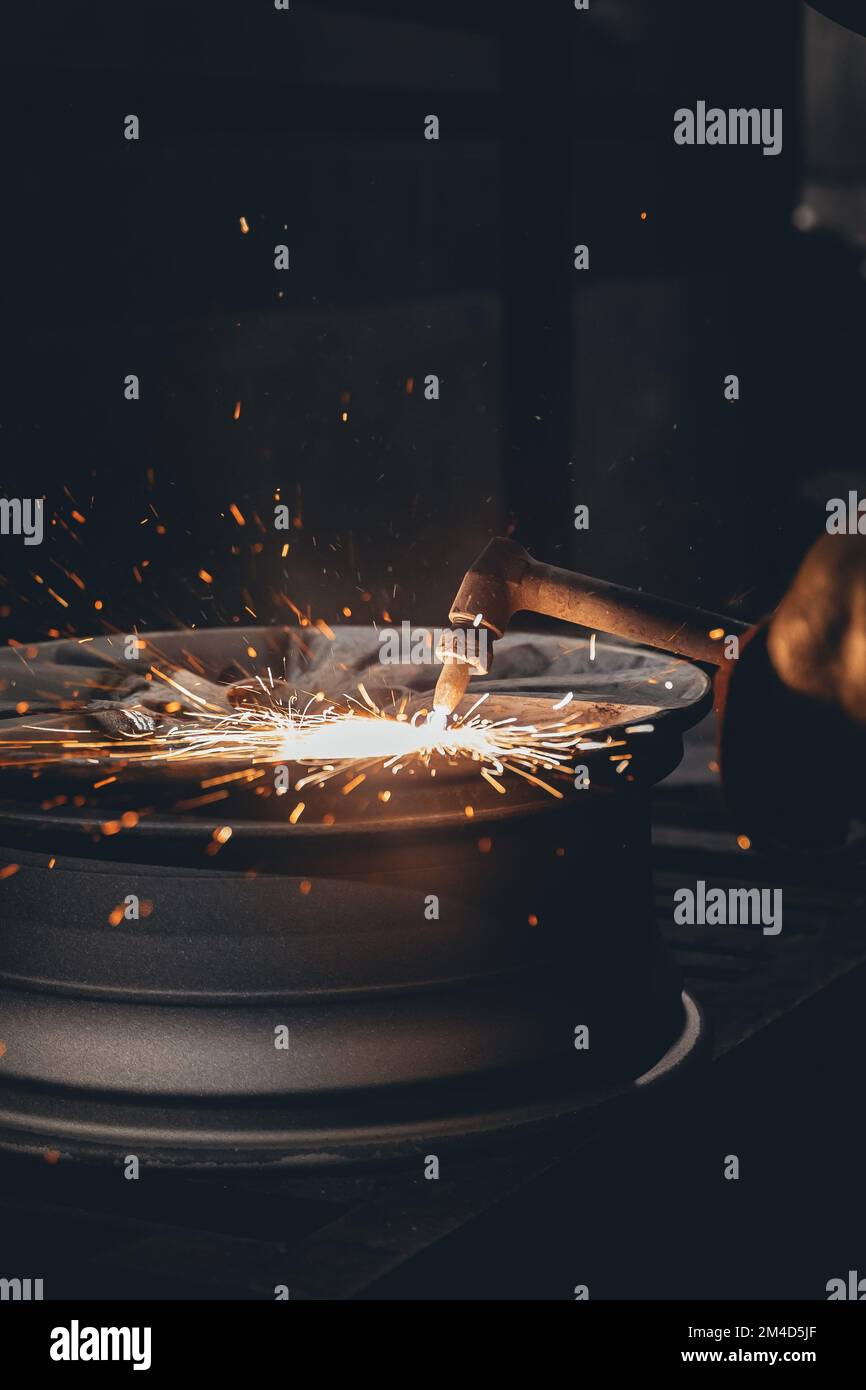 A vertical shot of a master welding and cutting a car disk wheel Stock ...