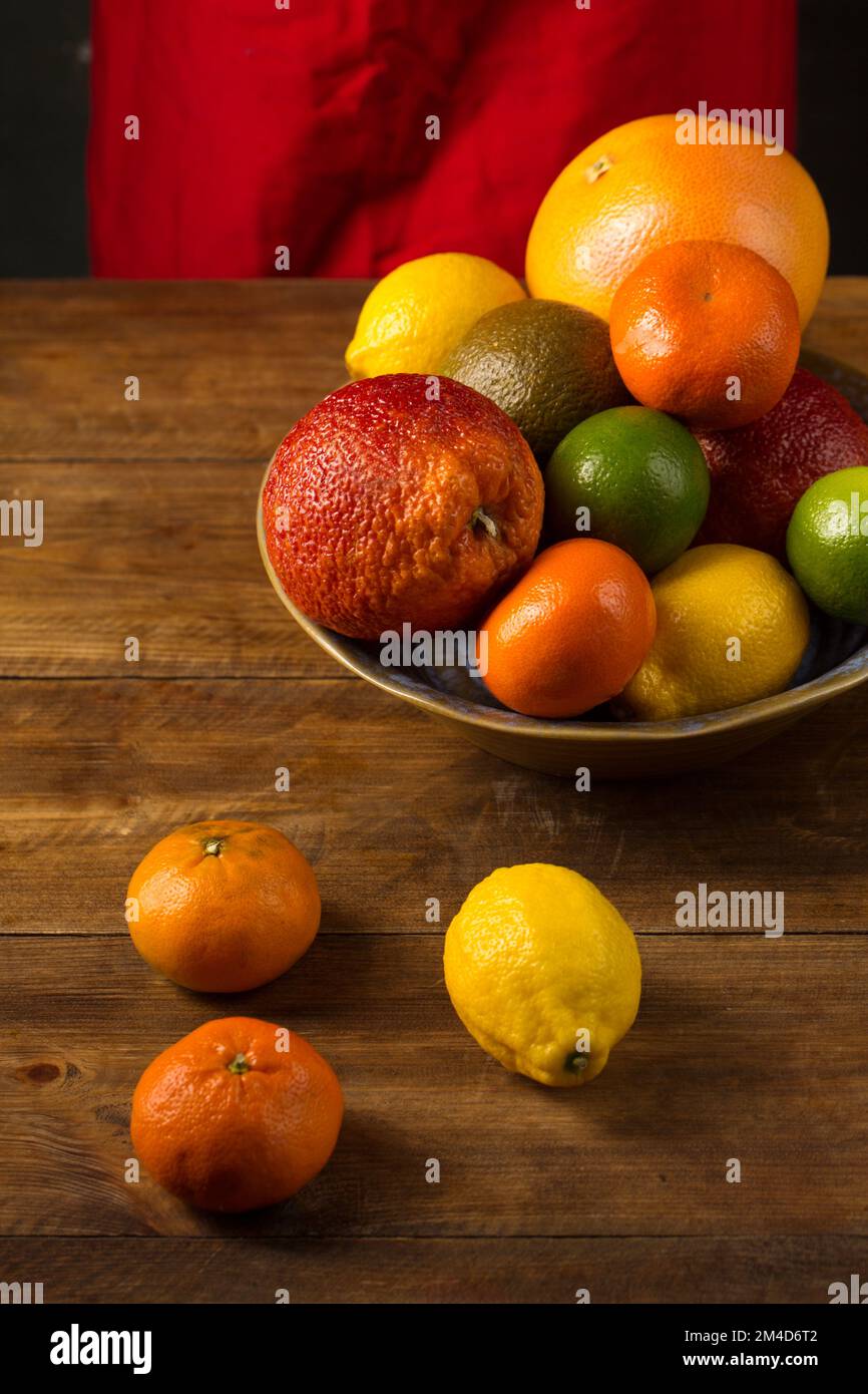 A variety of exotic citrus fruits in a large bowl on a dark background ...