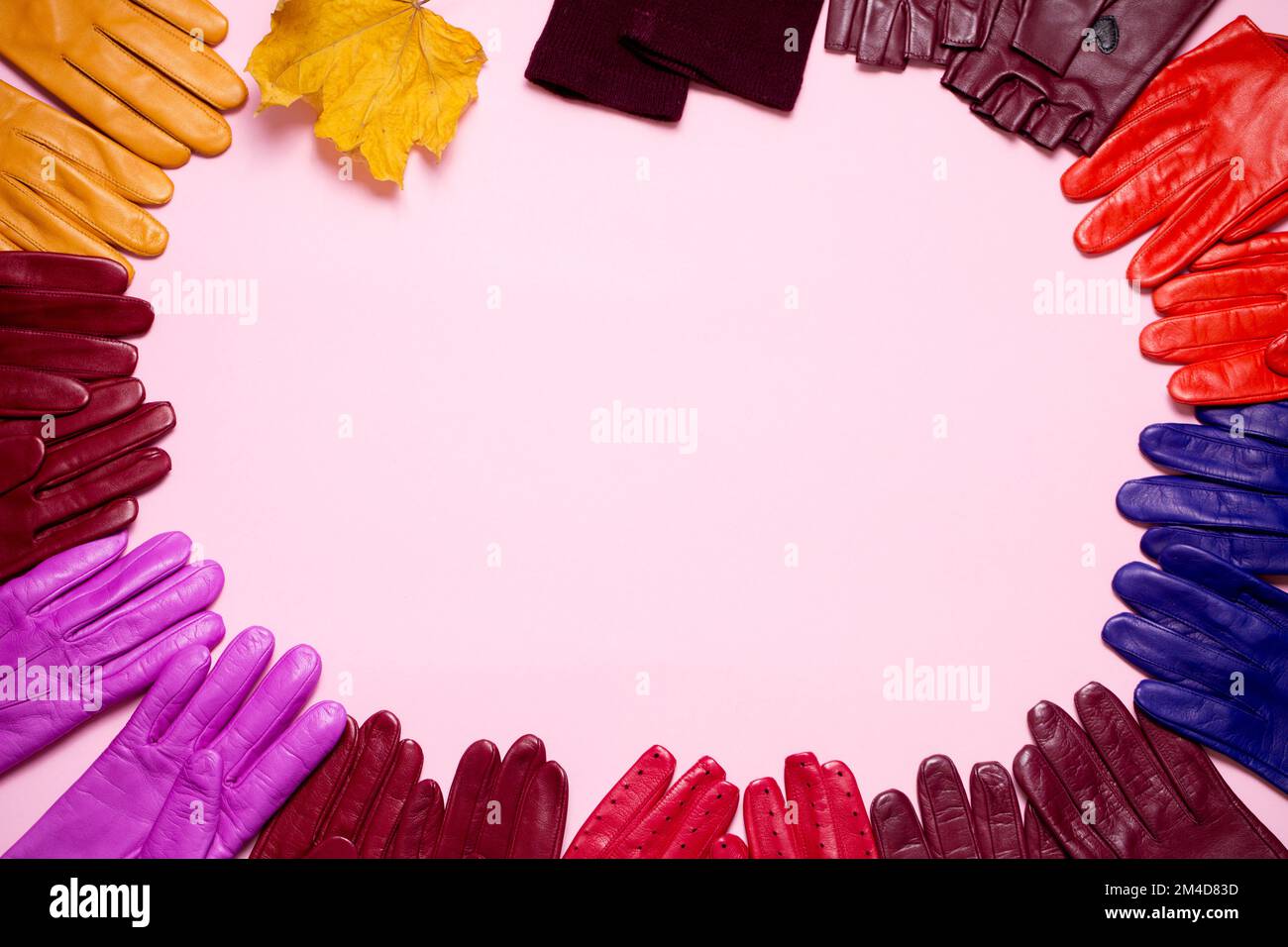 Many bright multi-colored gloves are laid out in a circle on a pink ...