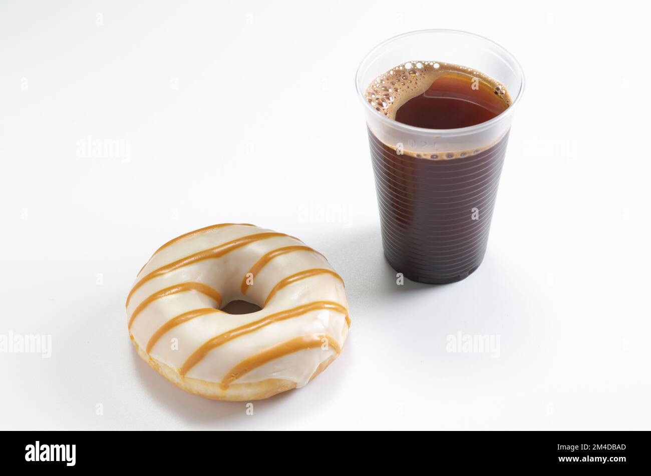 Plastic coffee cup with glazed donut on white table Stock Photo - Alamy