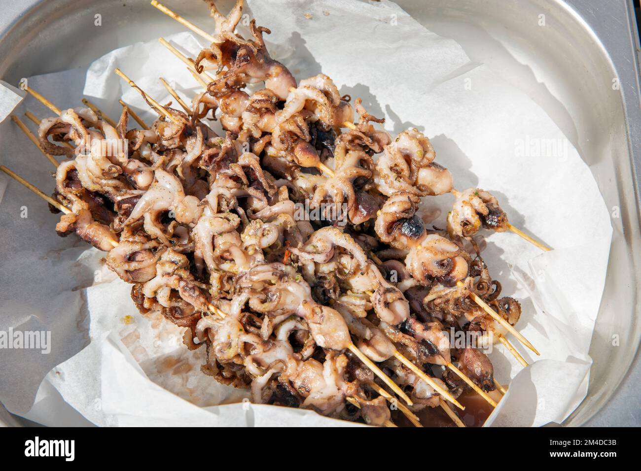 Grilled cuttlefish closeup on wooden skewers outdoor Stock Photo - Alamy