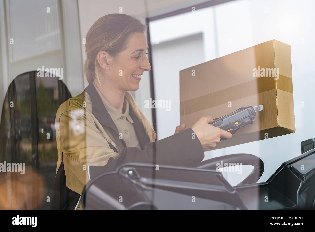 Delivery driver using barcode scanner checking pacel in a van outside a ...