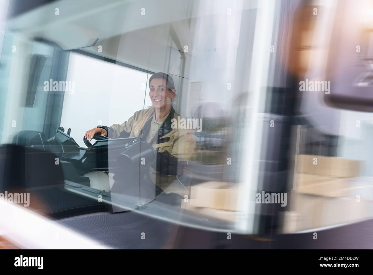 female delivery driver driving van with parcels on seat outside a ...
