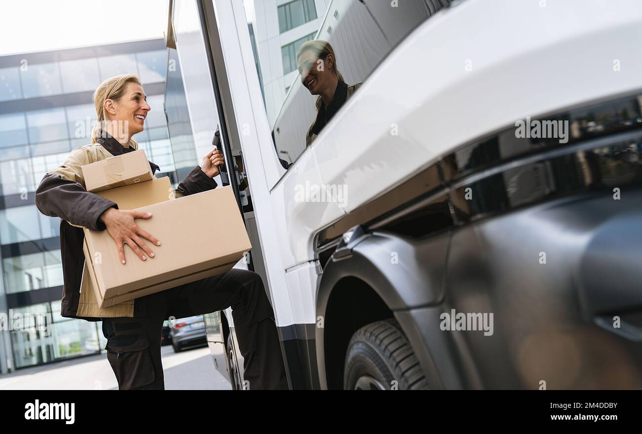 delivery agent holding parcels from a van to deliver it to a customer ...