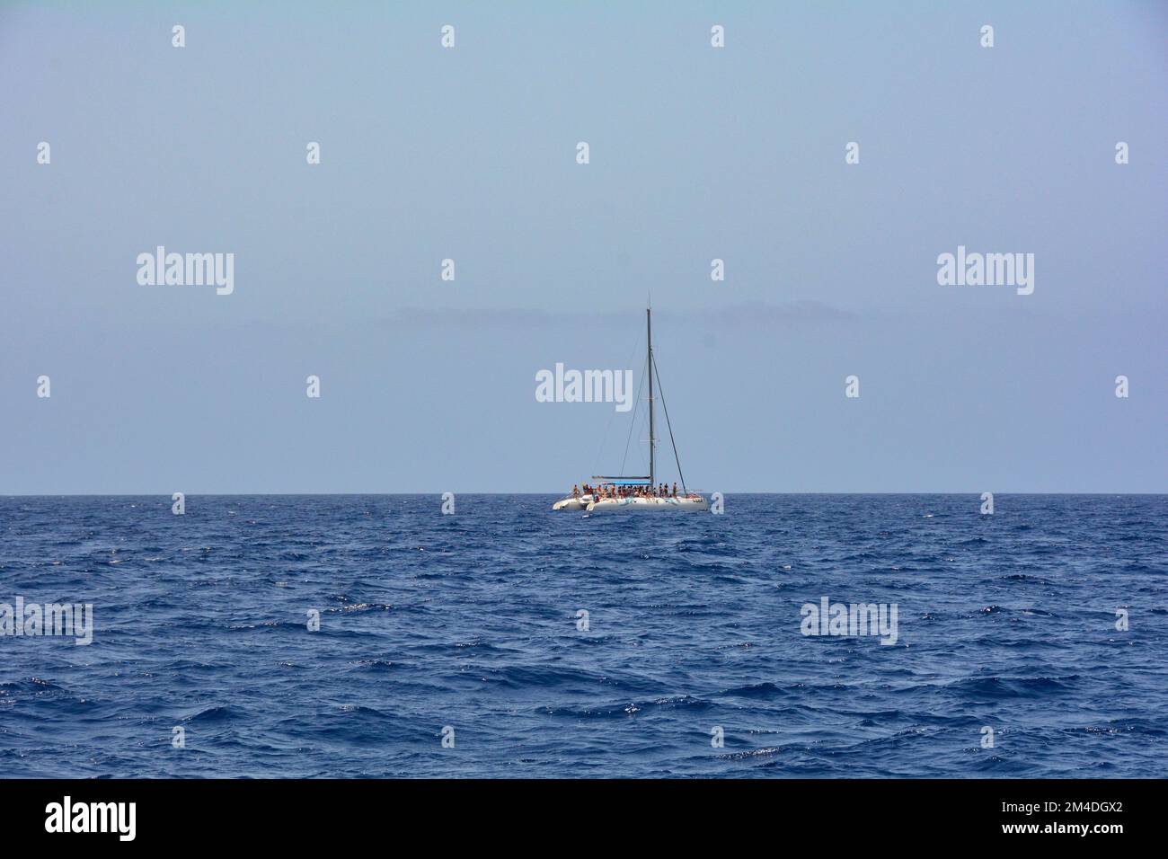 A catamaran with tourists on board sails across the open blue sea Stock ...