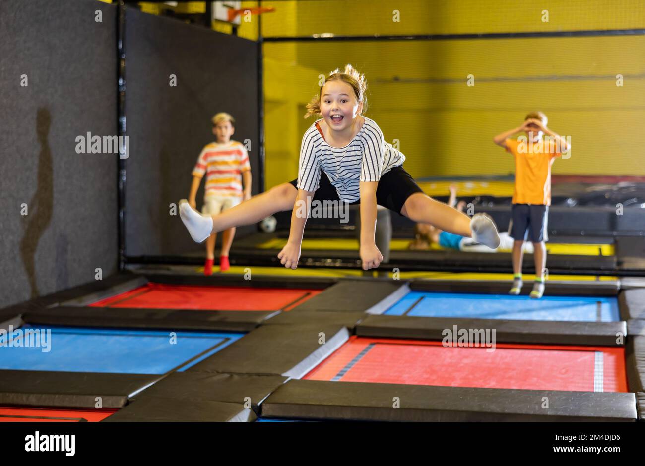 Tween girl doing split in jump in indoor trampoline arena Stock Photo ...