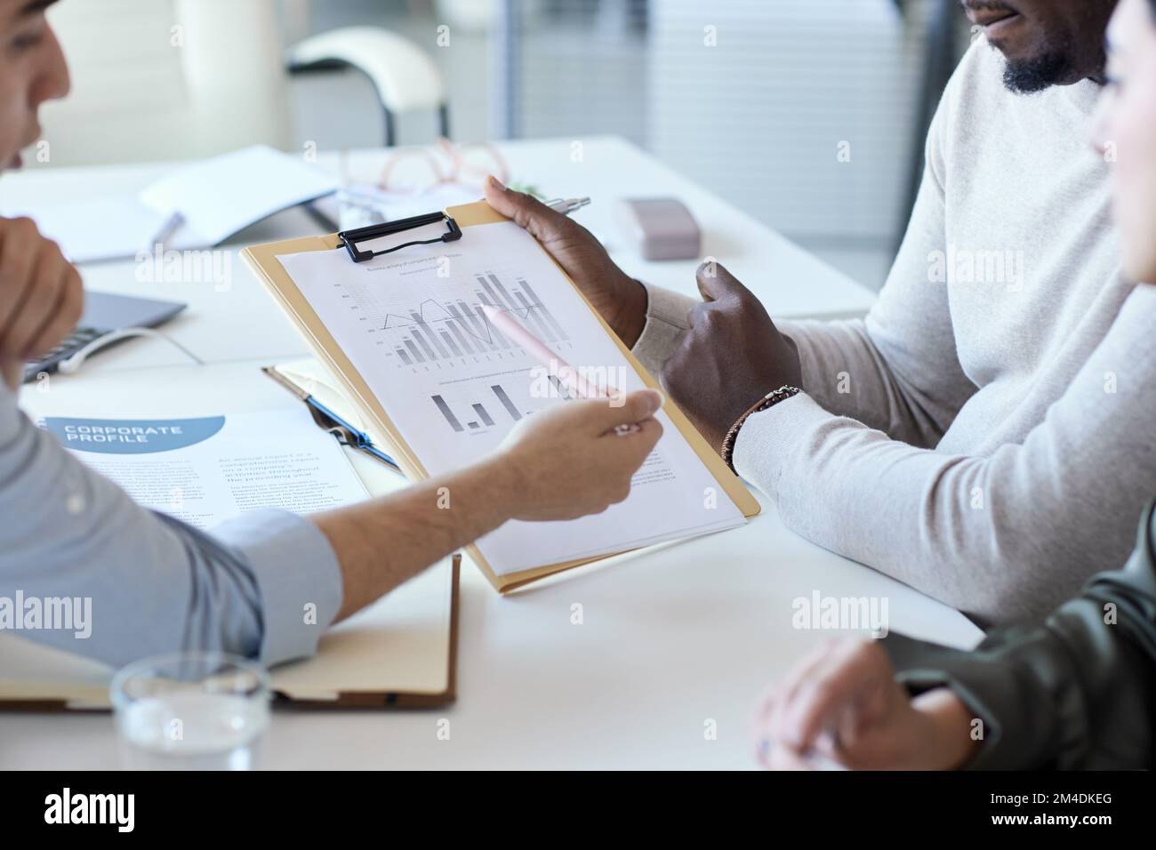 Close up of business team pointing at data chart on clipboard in ...
