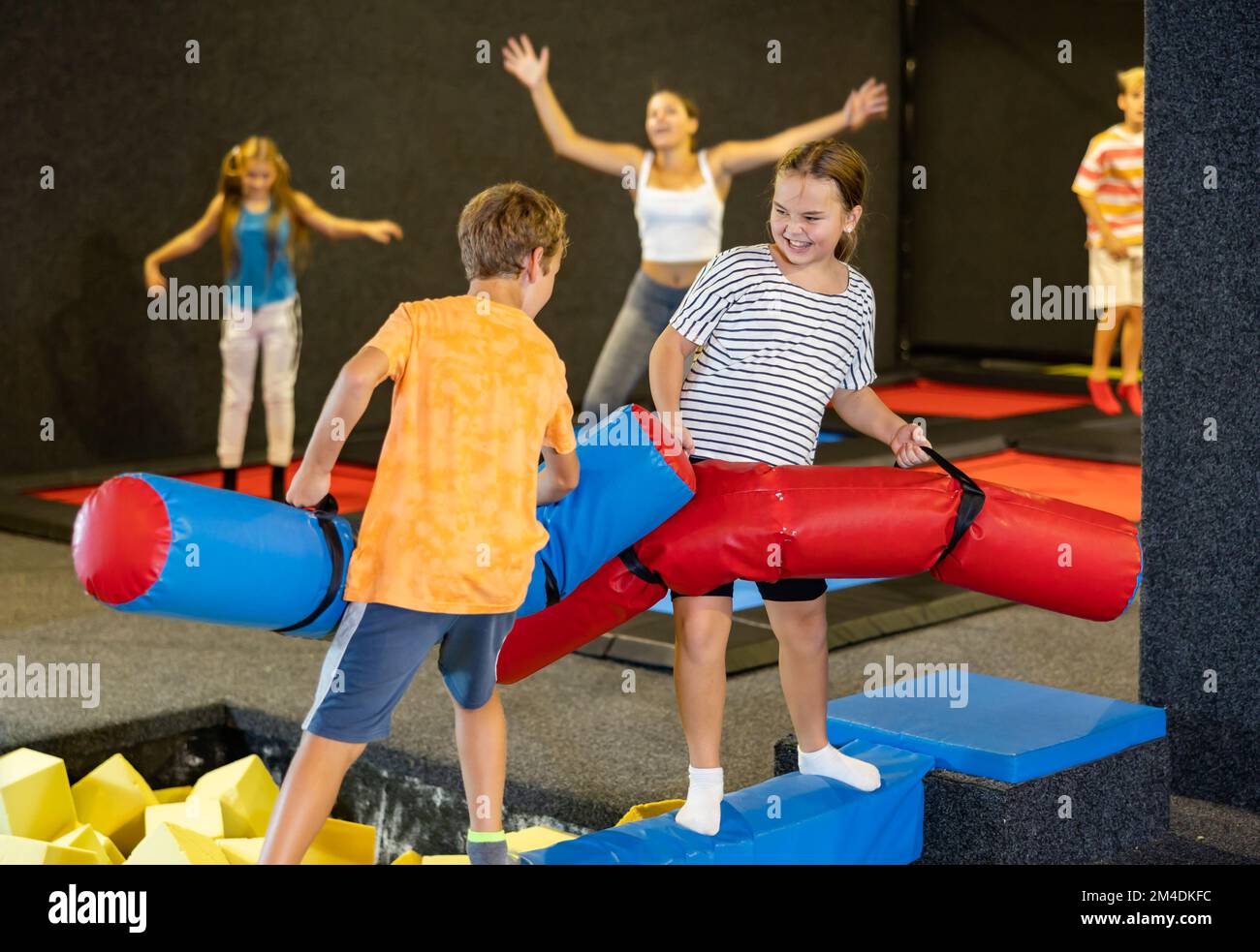 Preteen girl fighting by pugil stick with boy on inflatable beam Stock ...