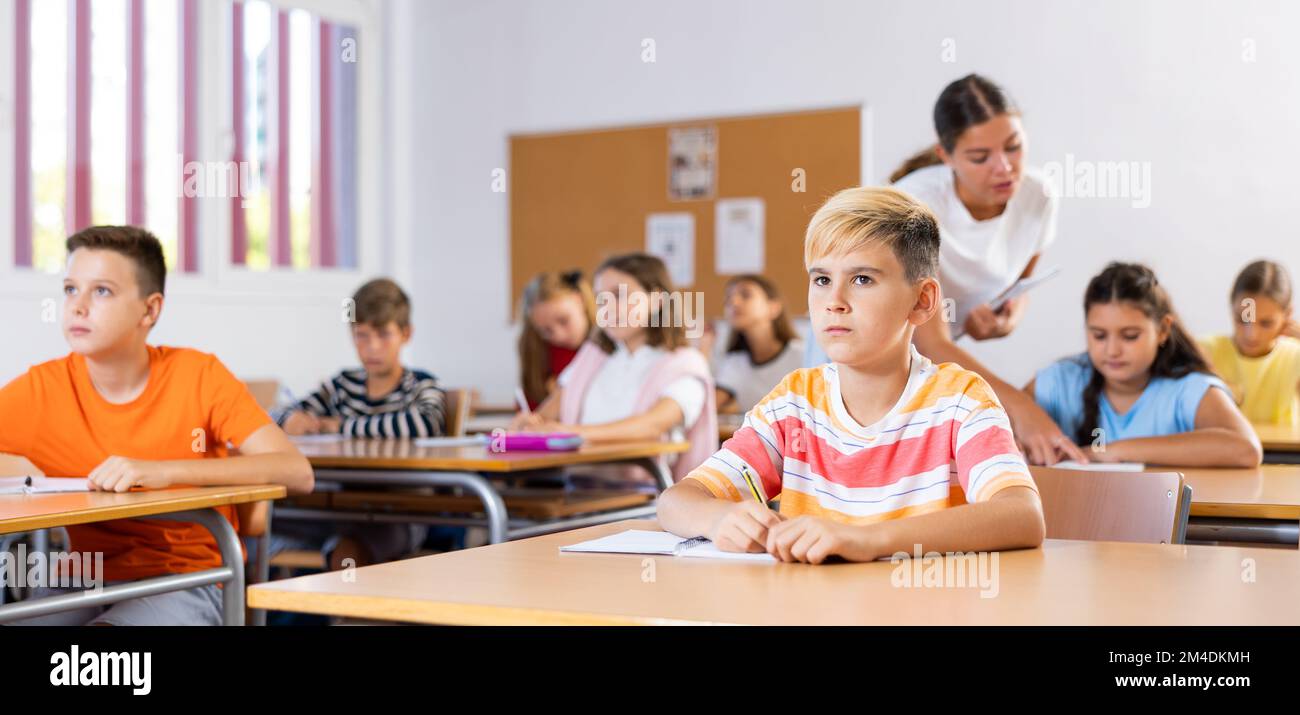 School boy sitting at the desk in classroom at lesson in primary school ...