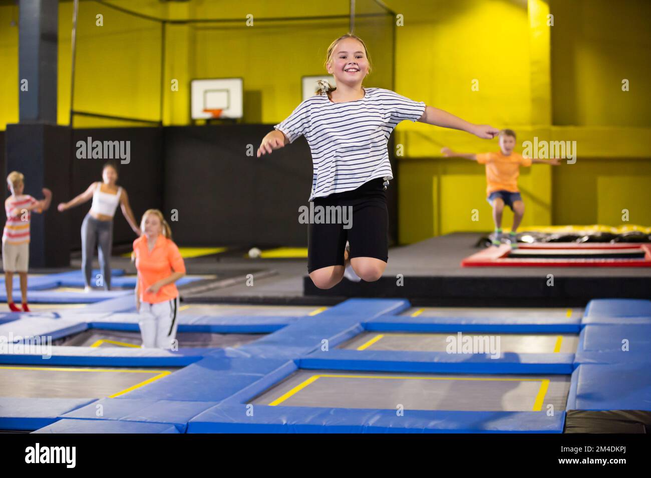 Happy cute little girl jumping on trampoline indoors Stock Photo - Alamy