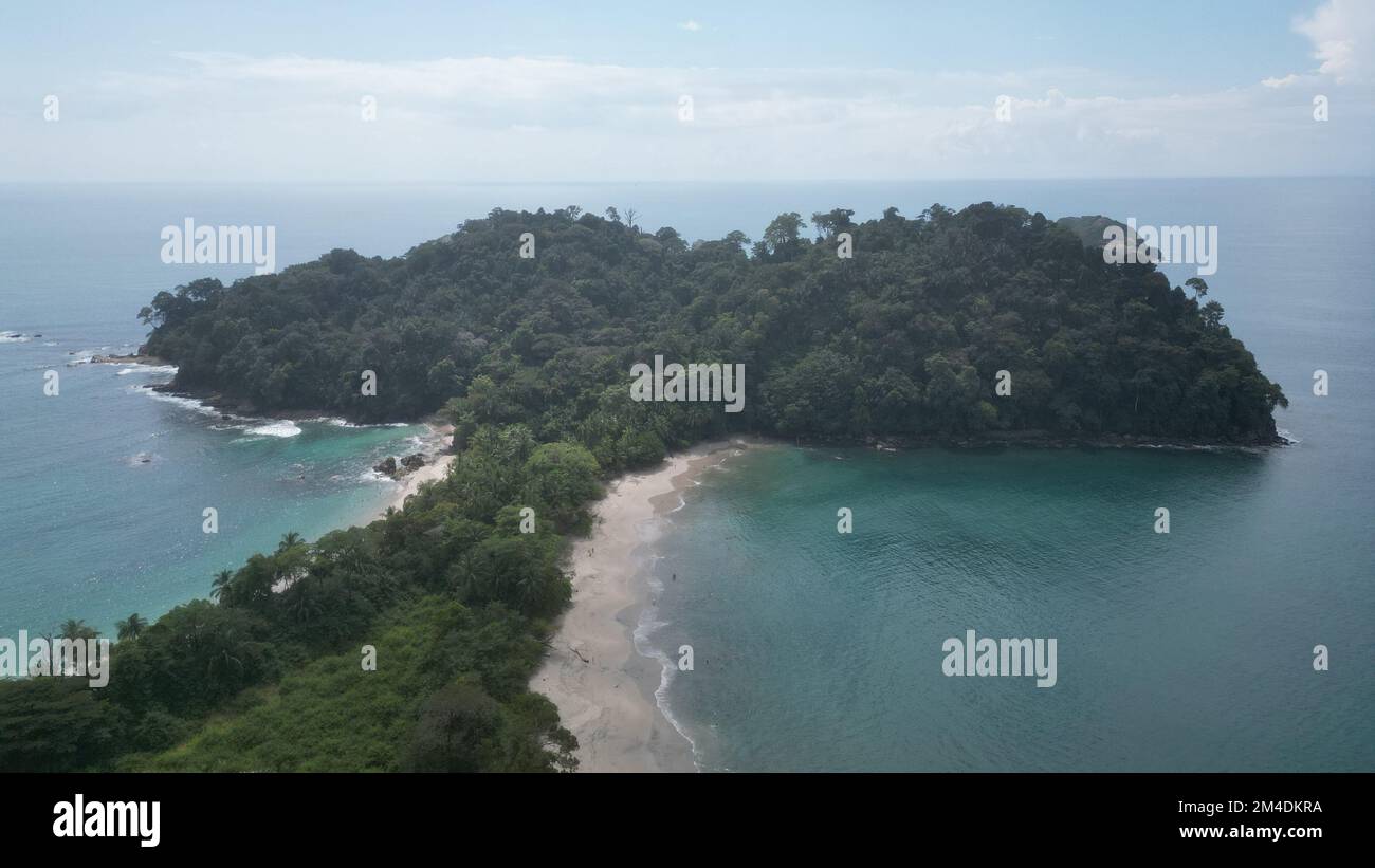 A drone shot of an island covered with greenery under blue cloudy sky ...