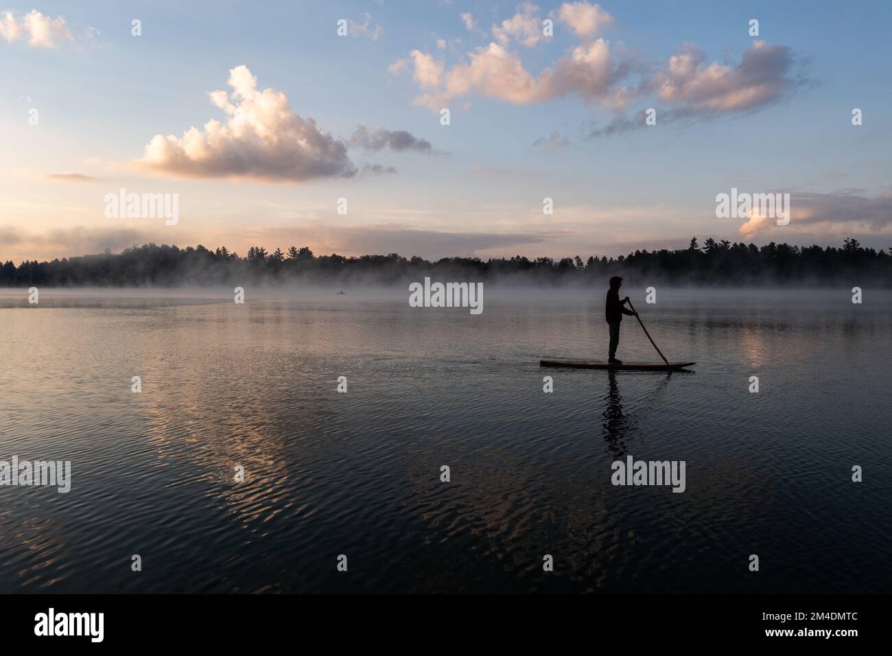 A beautiful view of a man on a puddle board on a sunset scene ...