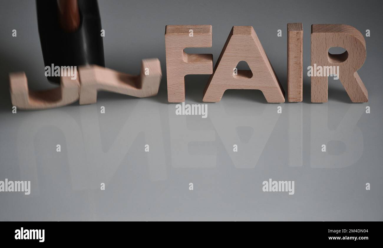 A wooden word UNFAIR with the first two letters smashed with a hammer ...