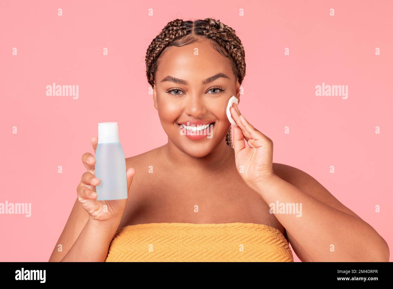 Happy african american oversize lady holding cotton pad and bottle with ...