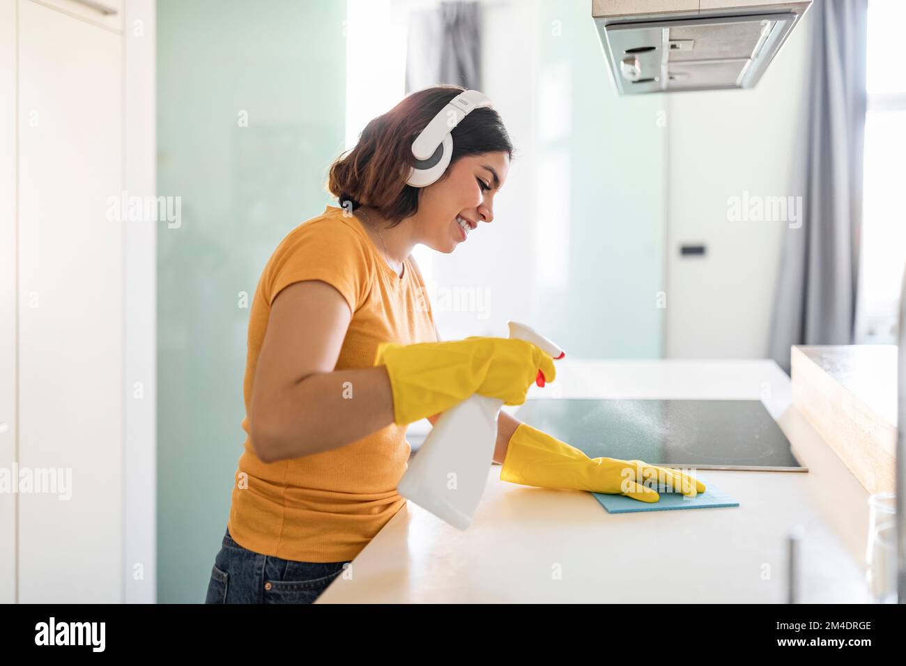 Smiling Arab Housewife Cleaning Kitchen Counter With Rag And Detergent ...