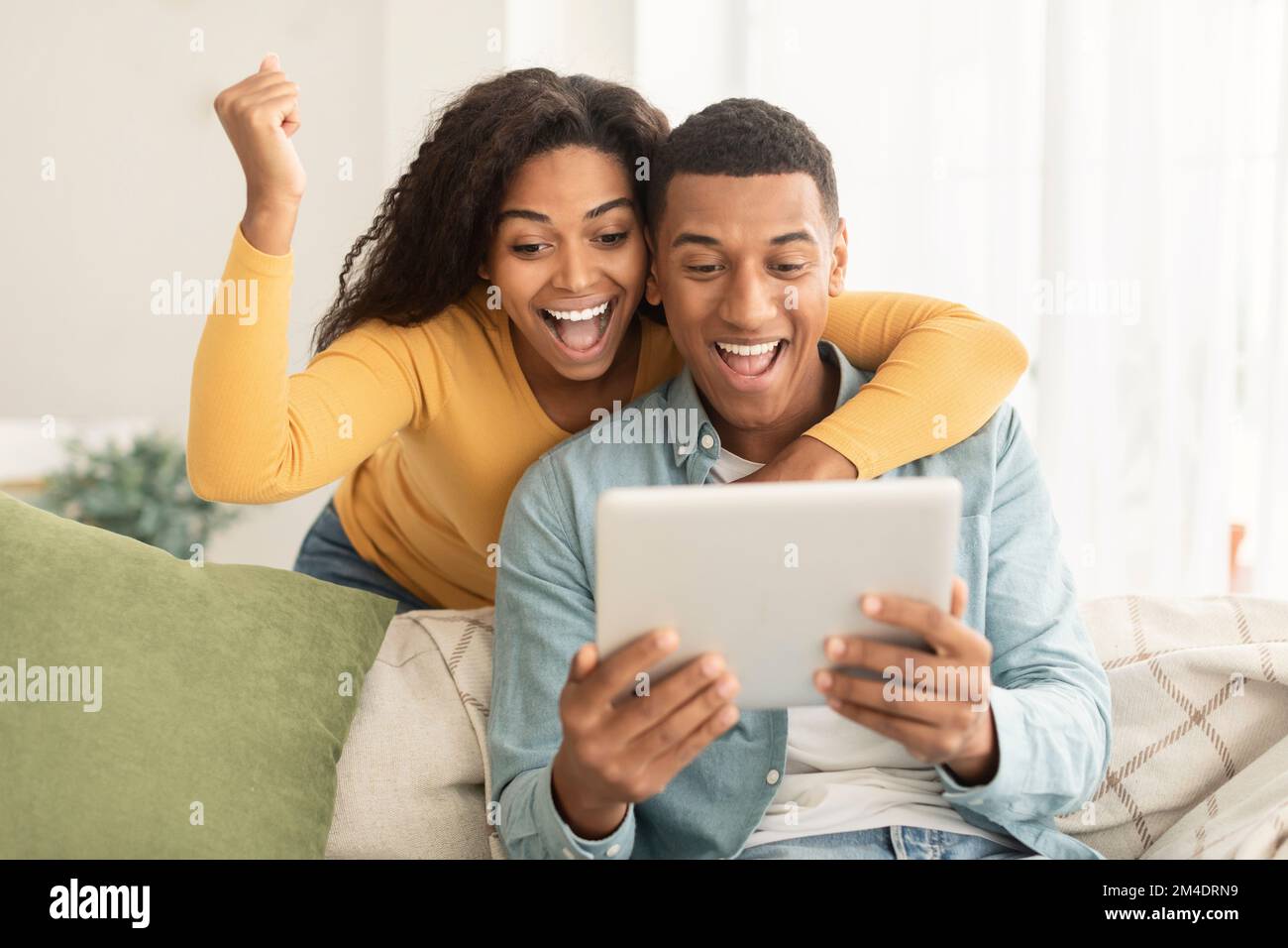Happy excited young african american wife and husband hugs, looks at ...