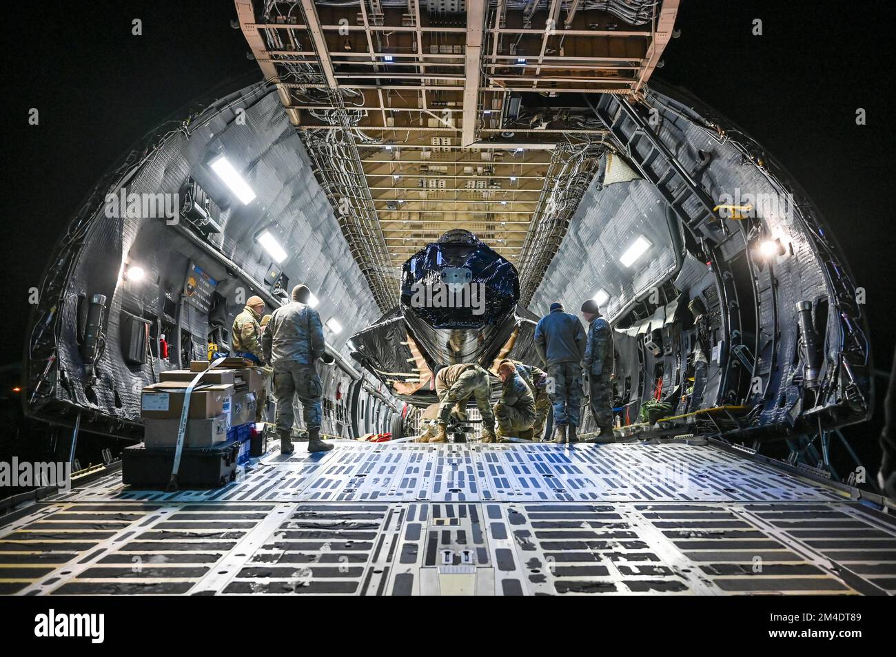Airmen attach a hitch to the front wheel of an F-22 Raptor fuselage ...