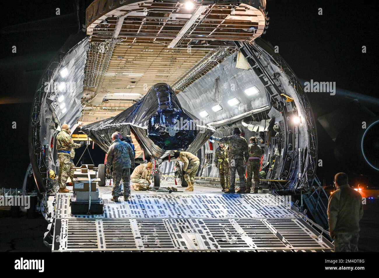 Airmen attach a hitch to the front wheel of an F-22 Raptor fuselage ...