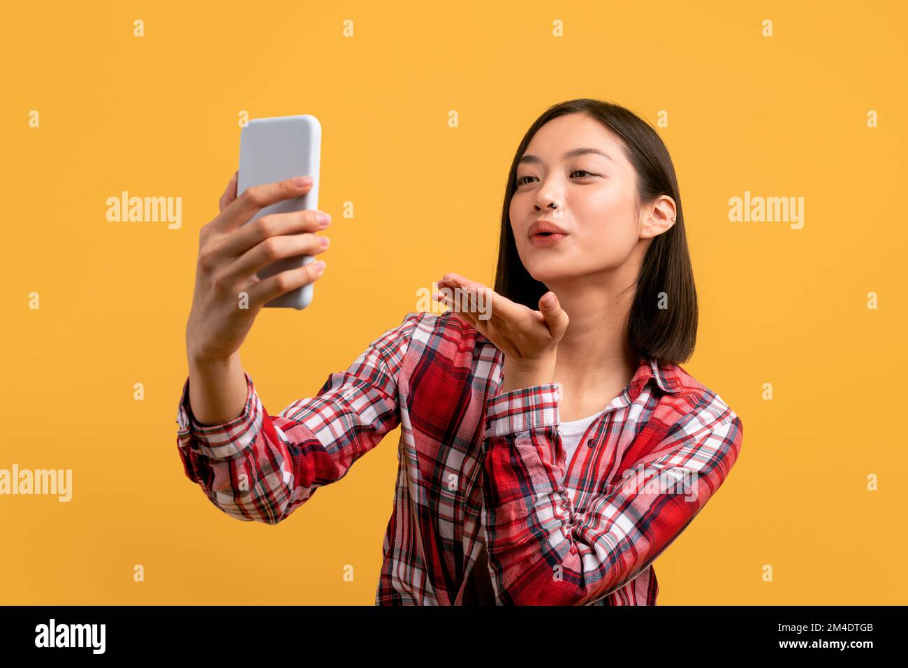 Joyful asian lady taking selfie with cellphone, sending air kiss and ...