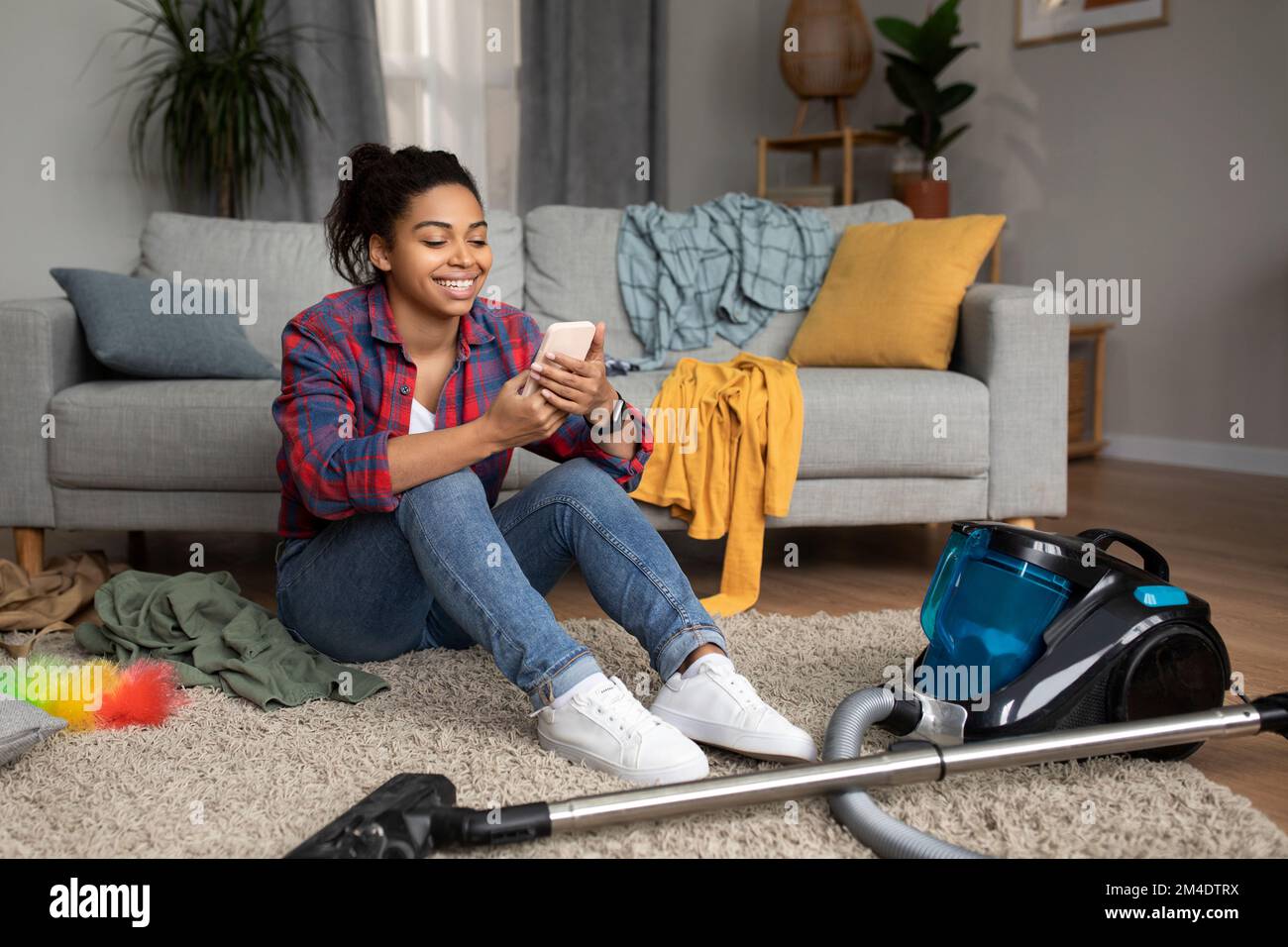 Glad millennial african american lady sits on floor in chaos and mess ...