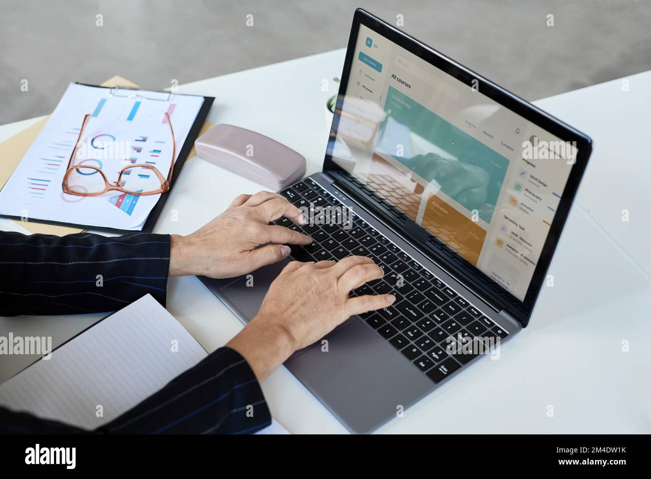 Close up of unrecognizable senior woman typing at laptop keyboard while working in office, copy ...