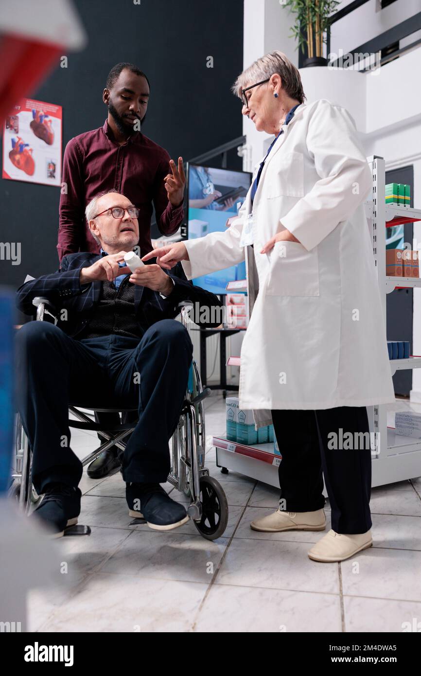 Drugstore worker discussing health care treatment with disabled ...