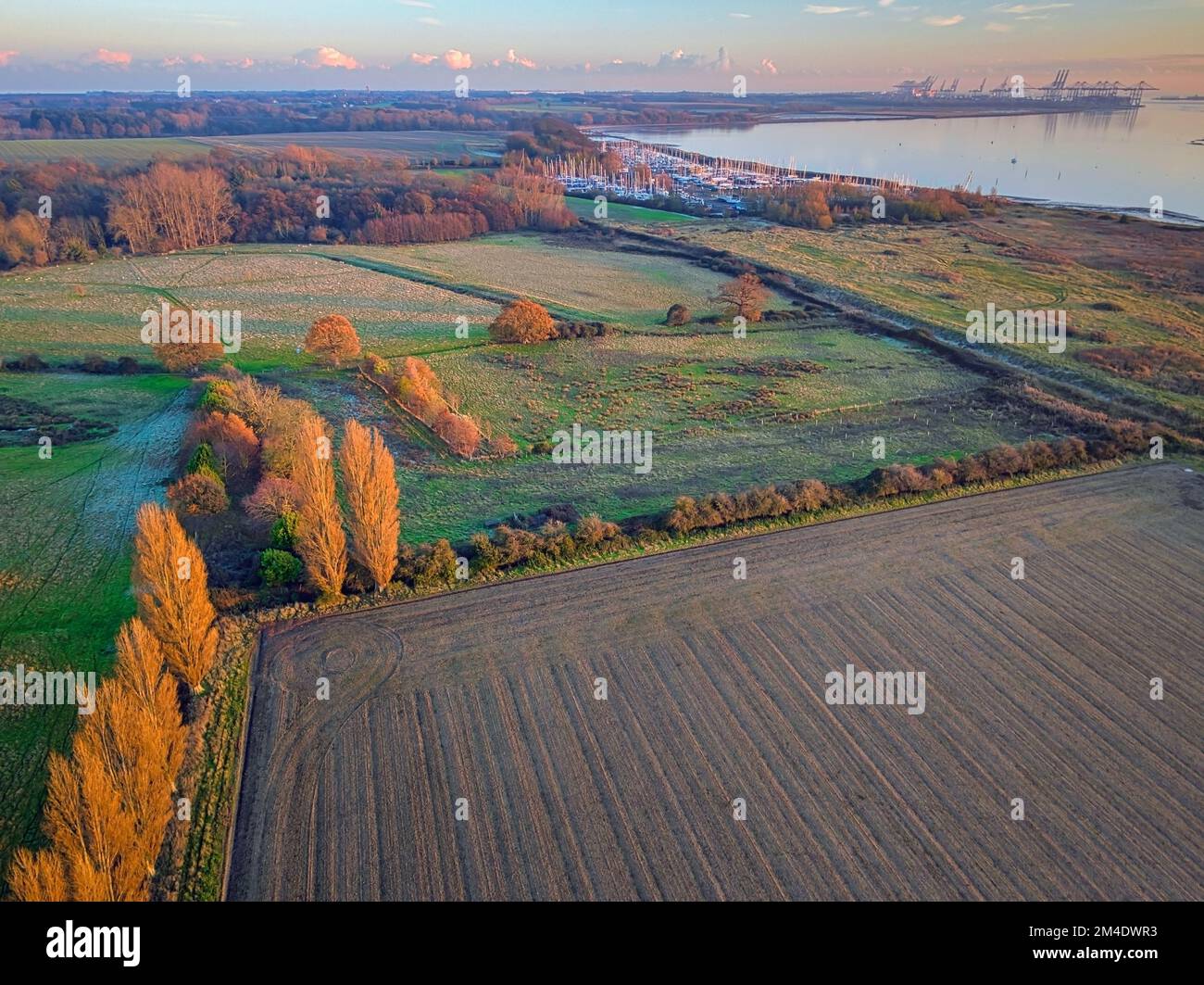 An aerial view of waterside agricultural fields at sunset in Suffolk ...